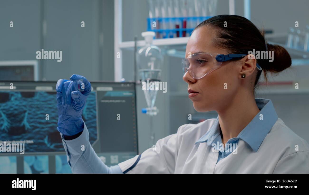 Chemistry specialist analyzing blood sample on glass in laboratory ...