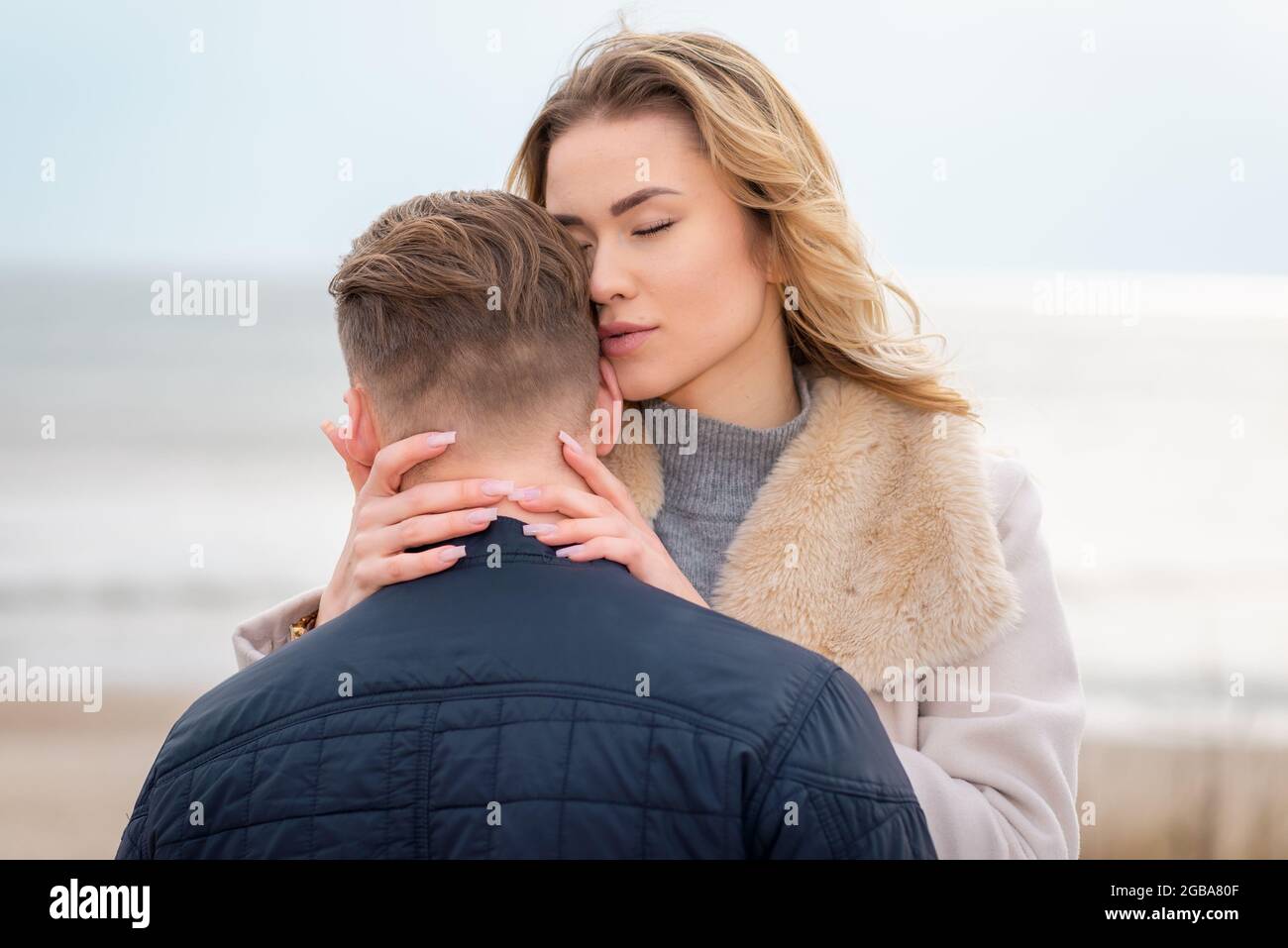 young beautiful stylish couple in spring on the beach. Hug each other ...