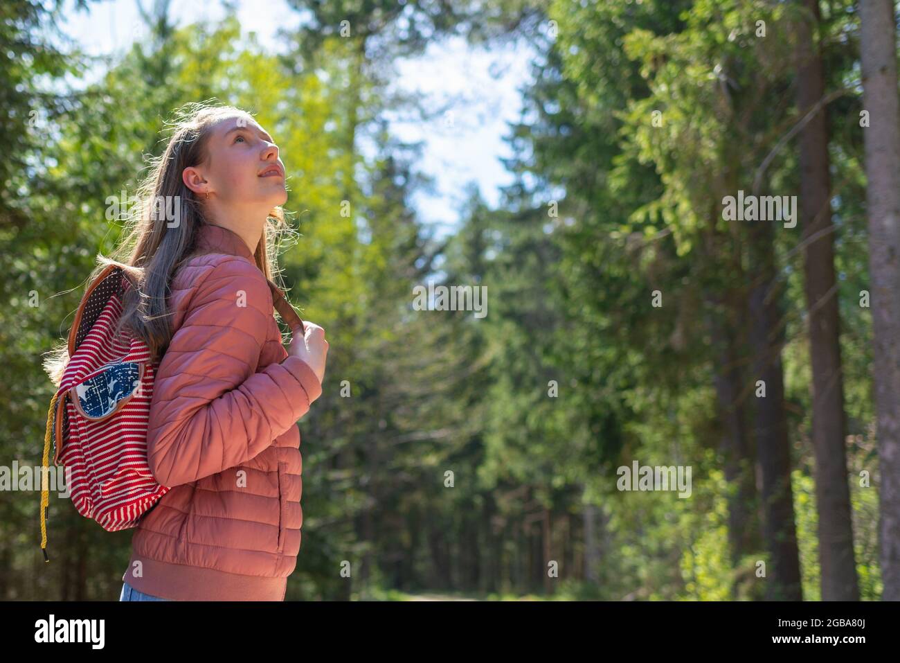 Pretty one teen young tourist girl relaxing on forests road.Teenage with backpack on green ...