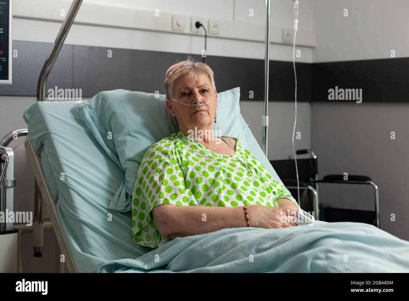 Portrait of hospitalized retired sick woman looking into camera resting ...
