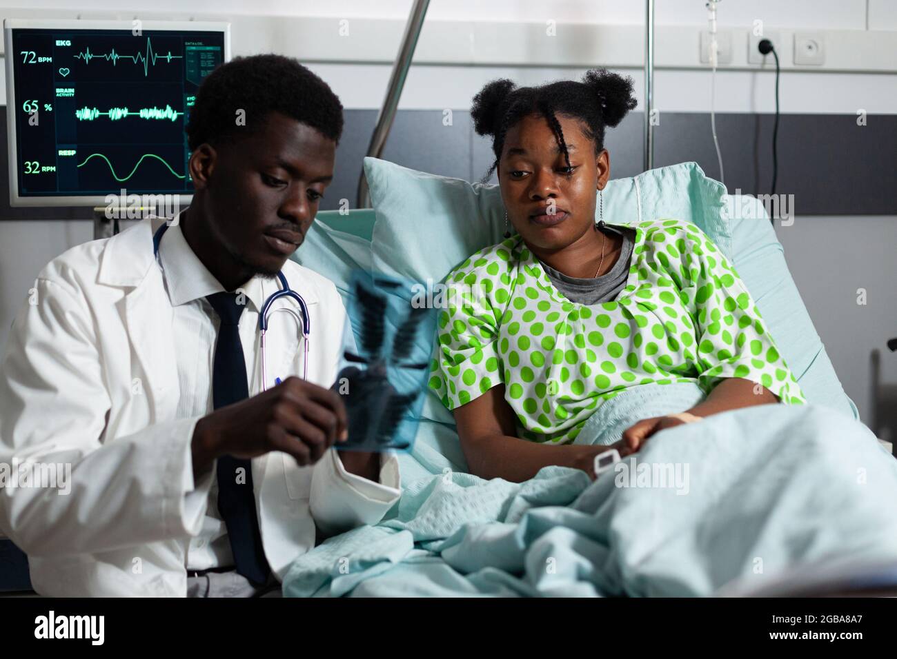 African american doctor and patient looking at x ray in hospital ward ...