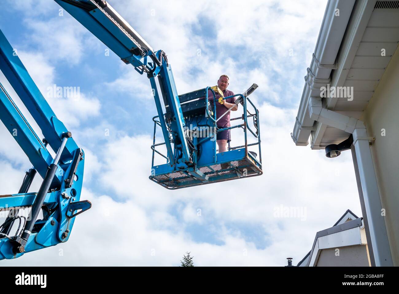 Worker on a aerial access platform, cherry picker, cleaning house Stock ...