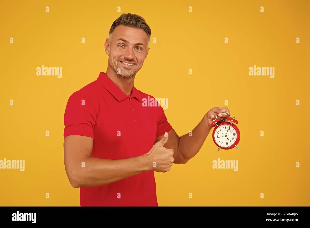 Accuracy and precision. Happy man hold alarm clock showing thumbs up ...