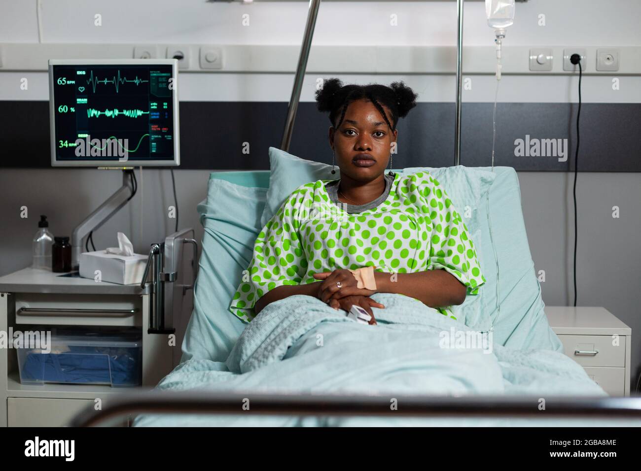 Portrait of african american girl sitting in hospital ward with medical ...