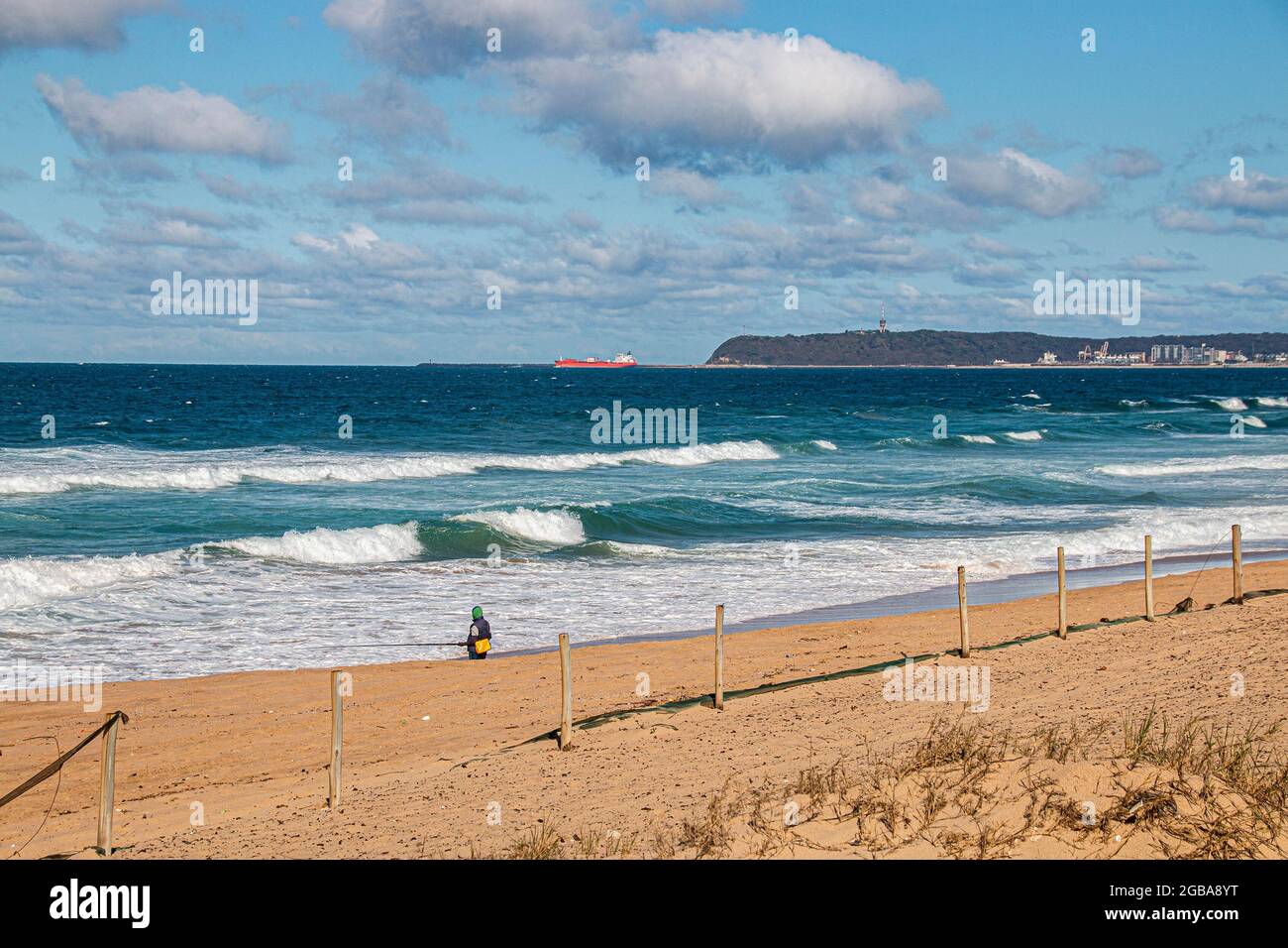 Red cargo ship leaving harbour with bluff in background Stock Photo - Alamy