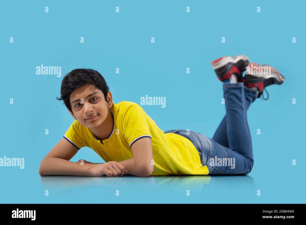 A TEENAGE BOY RESTING ON FLOOR AND POSING IN FRONT OF CAMERA Stock ...
