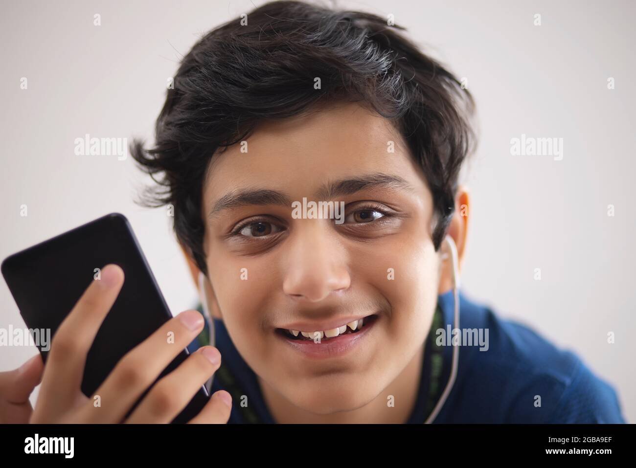 A HAPPY TEENAGE BOY LOOKING AT CAMERA WHILE HOLDING MOBILE PHONE Stock ...