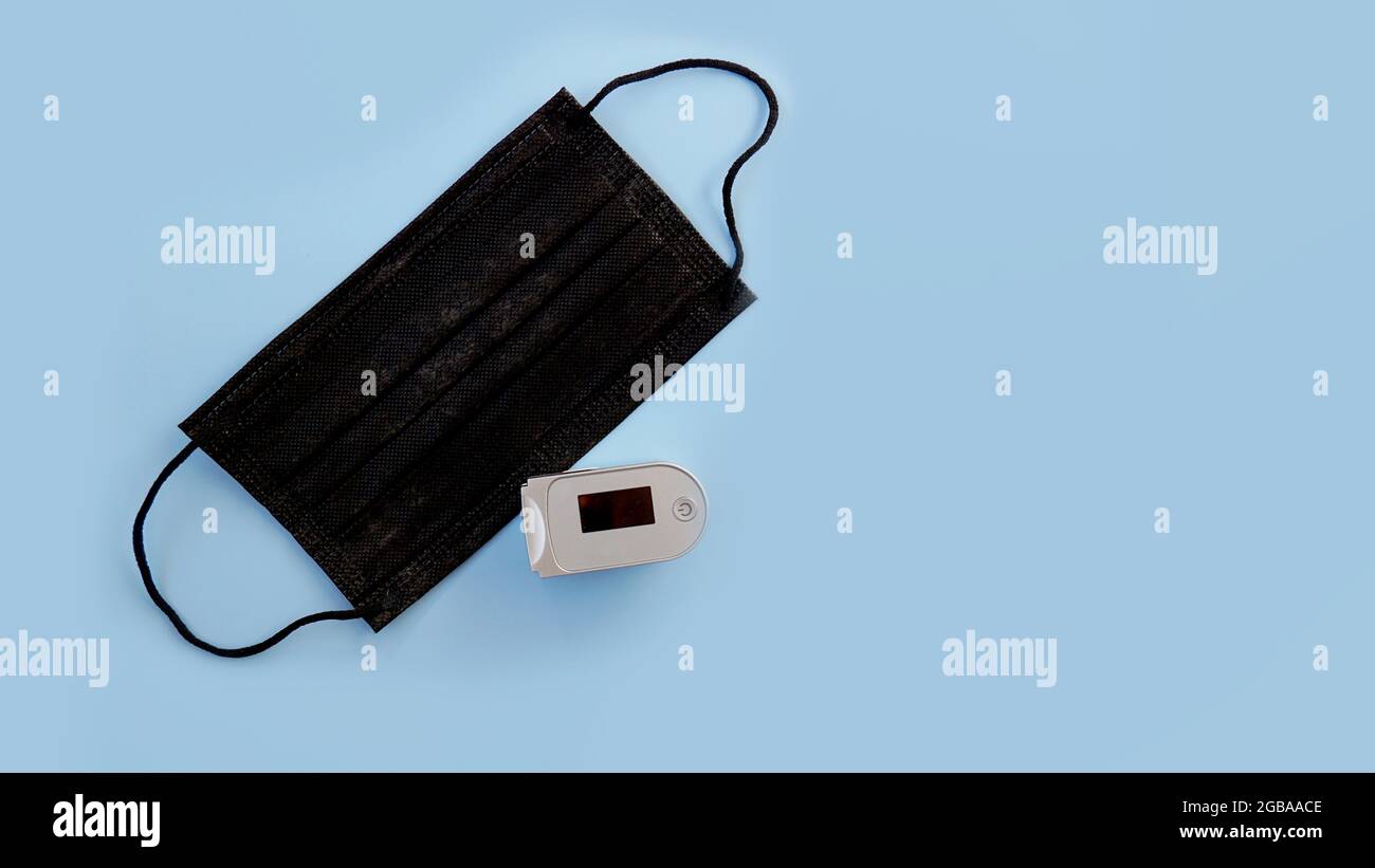 Medical black mask and oximeter on a blue background. Copy space Stock ...