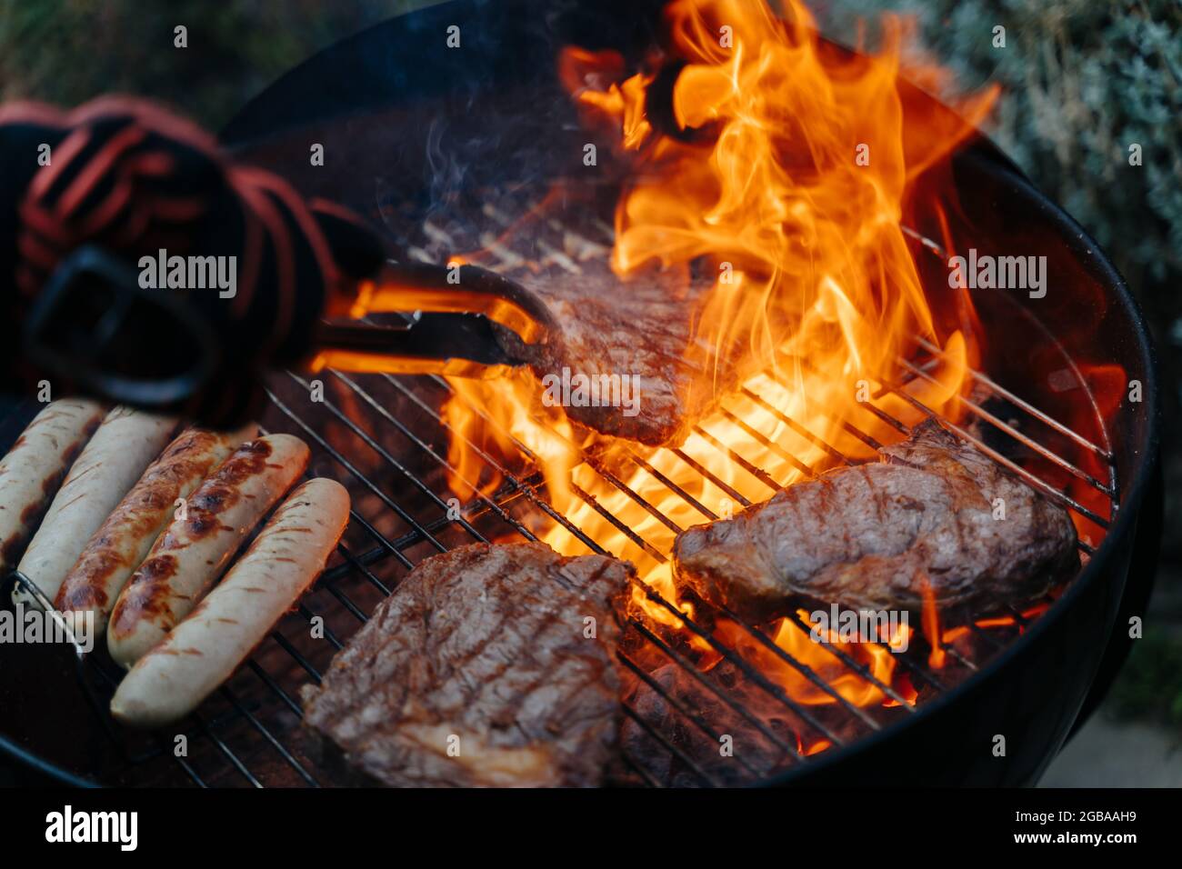 man turning steak on barbeque grill Stock Photo - Alamy