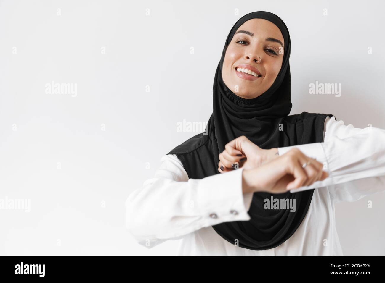 A positive muslim woman in hijab dancing with raised arms in the white ...