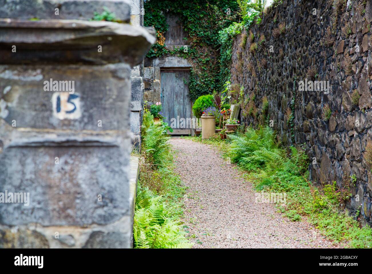 Loose stone alley with stone wall and house number, with shed door at ...