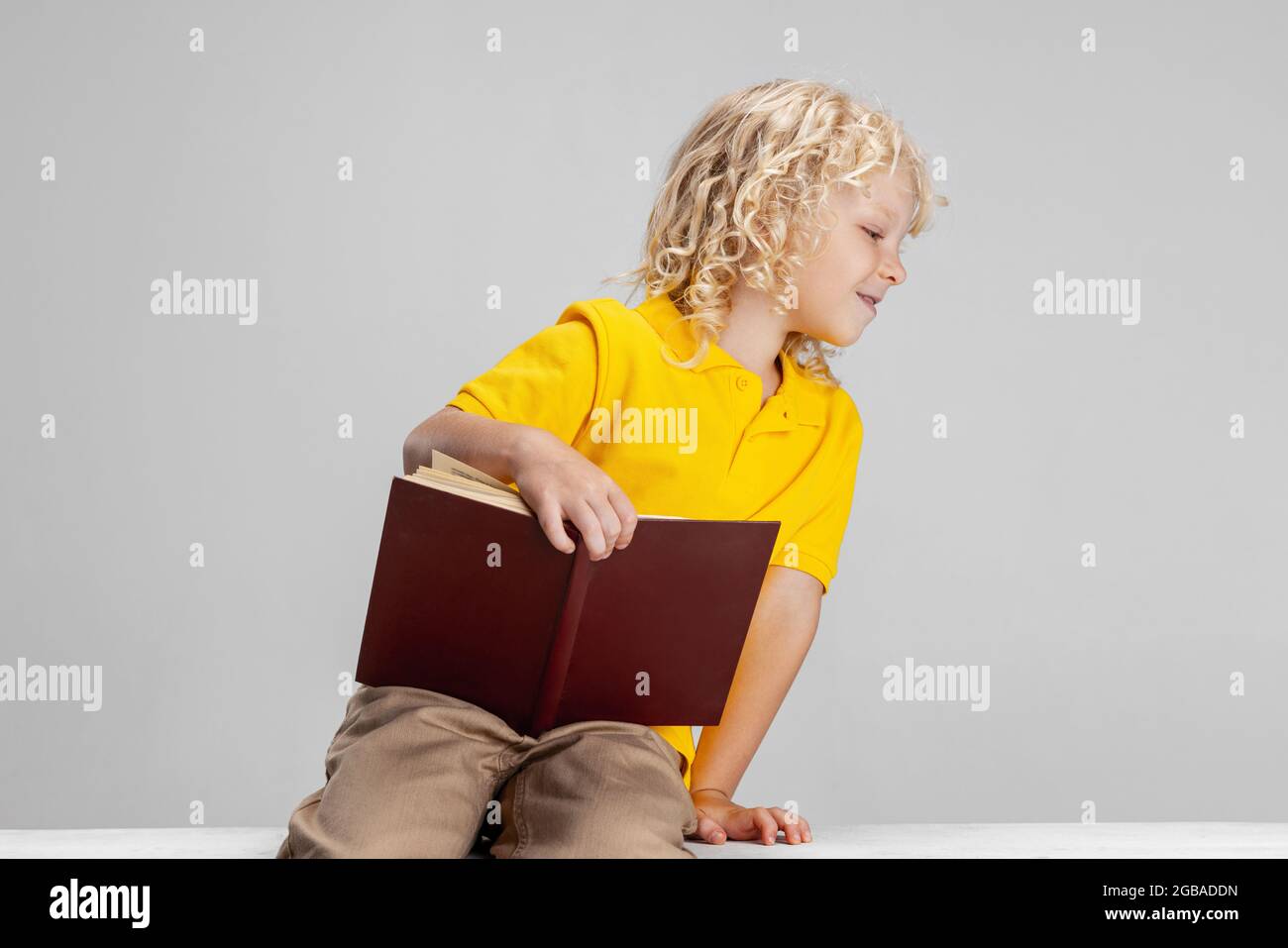 Portrait of one cute little curly preschool boy reading book isolated ...