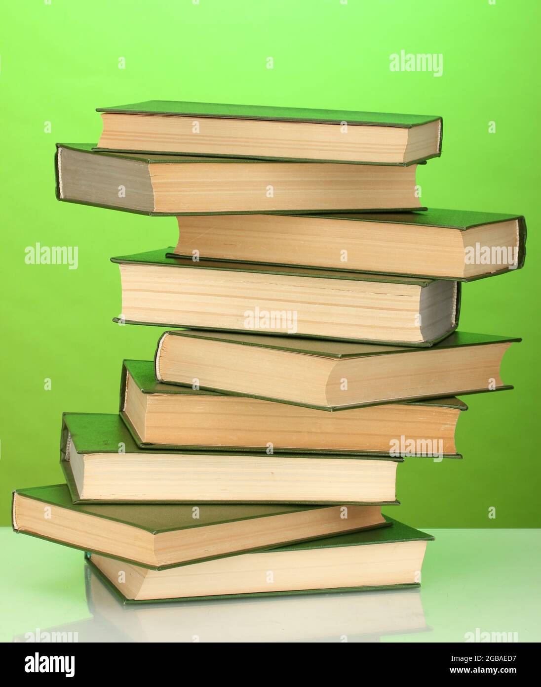 Tower of books on green background Stock Photo - Alamy