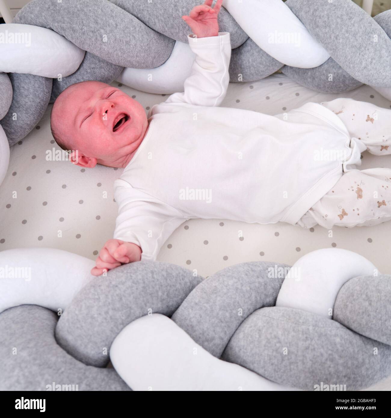 Portrait of a baby boy aged one month crying in a crib. Caucasian ...