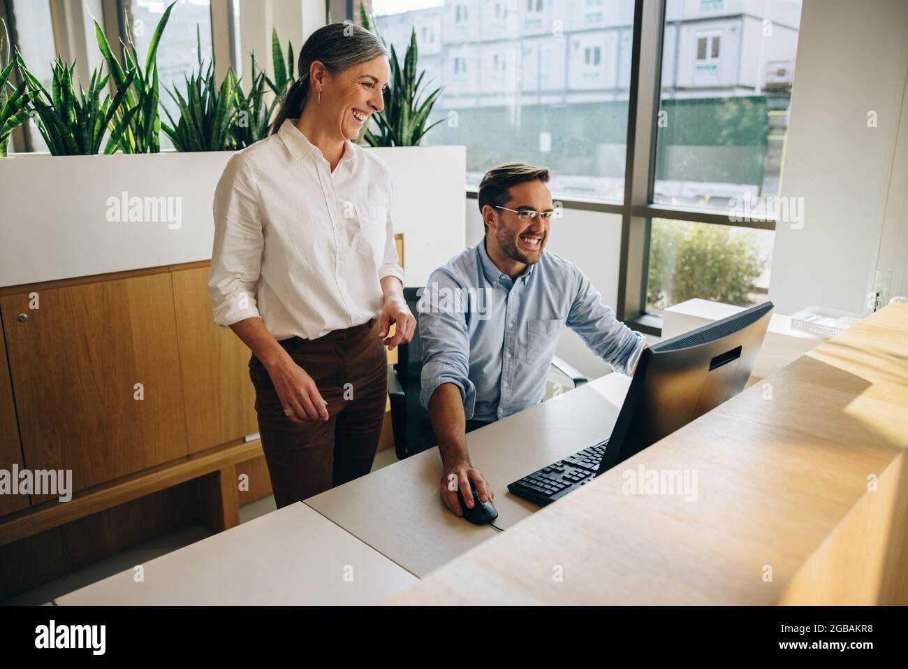 Happy female executive supervising her coworker work on computer ...