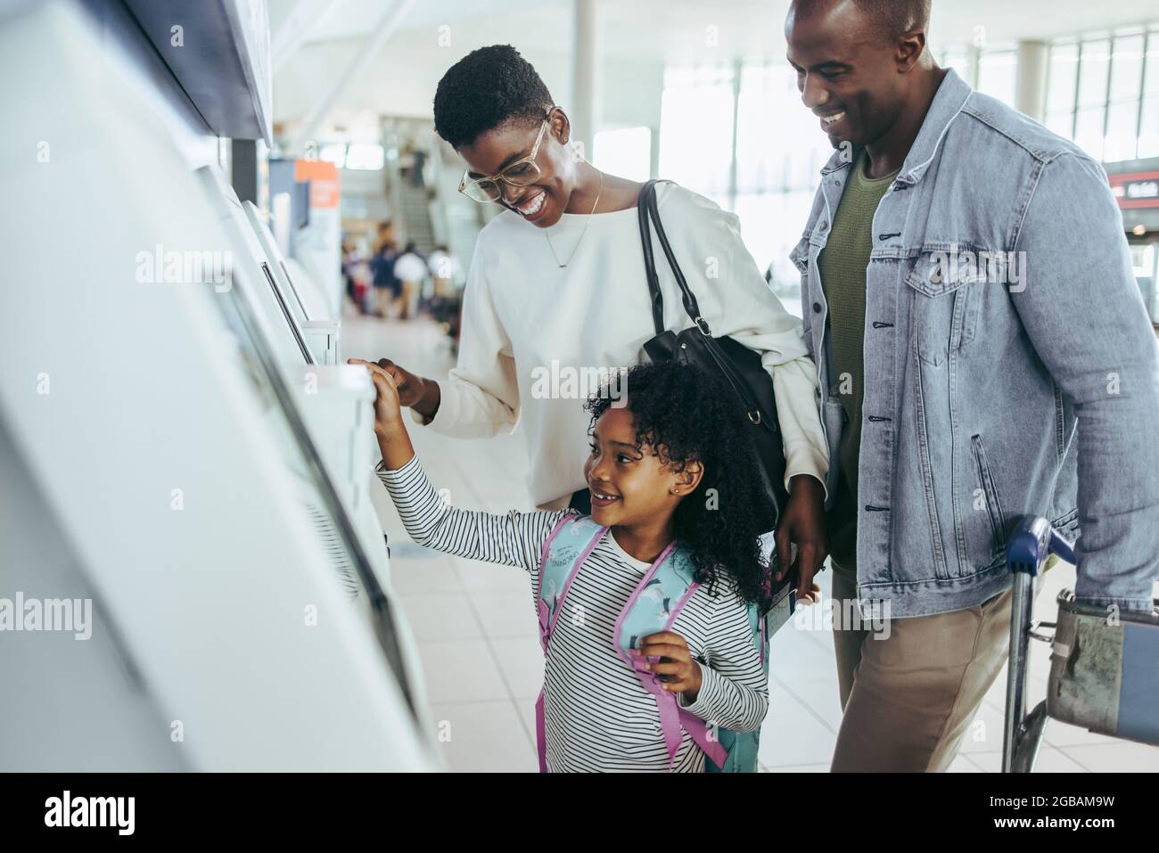 Small girl happy to use self service check in machine at airport with ...