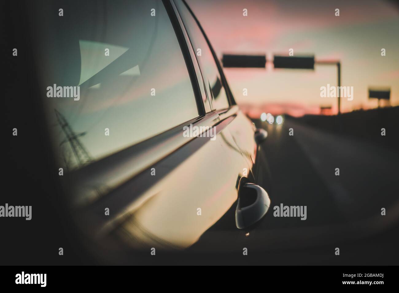 Rear car mirror reflecting sunset sky and blurry car headlights at ...
