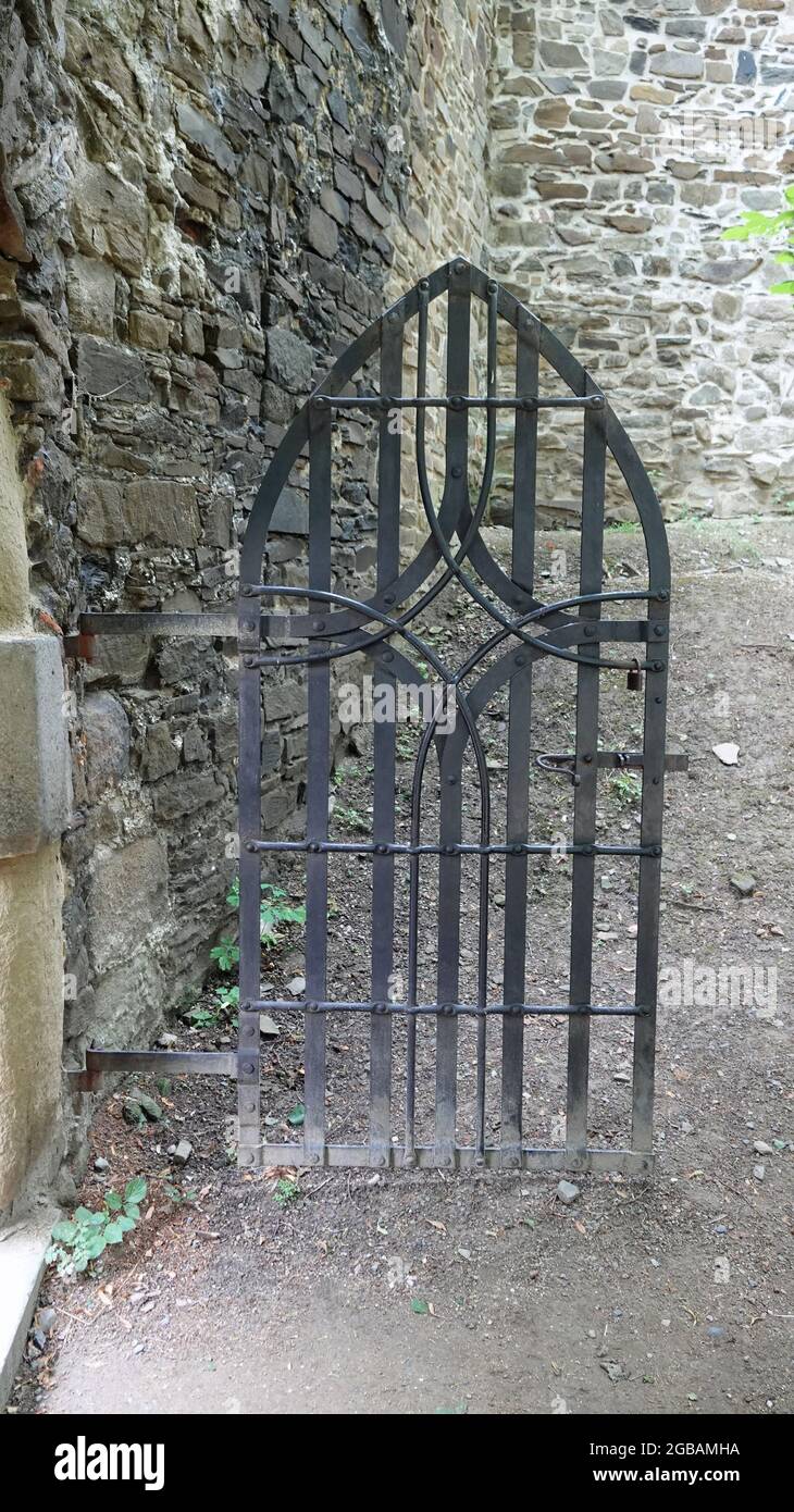 Iron gate at Helfstyn castle. In the background is a stone wall ...
