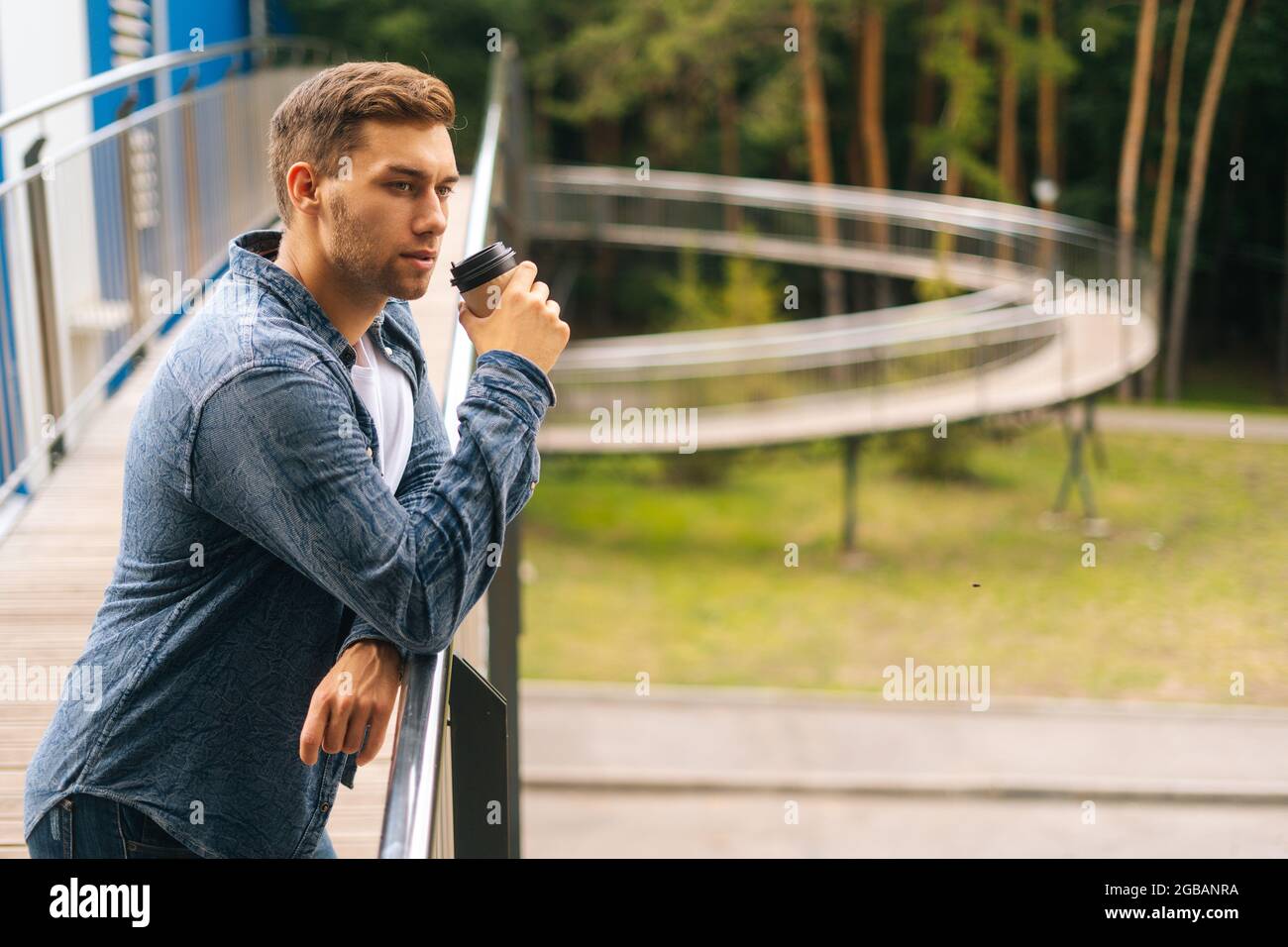 Side view of confident thoughtful young man standing on balcony terrace ...