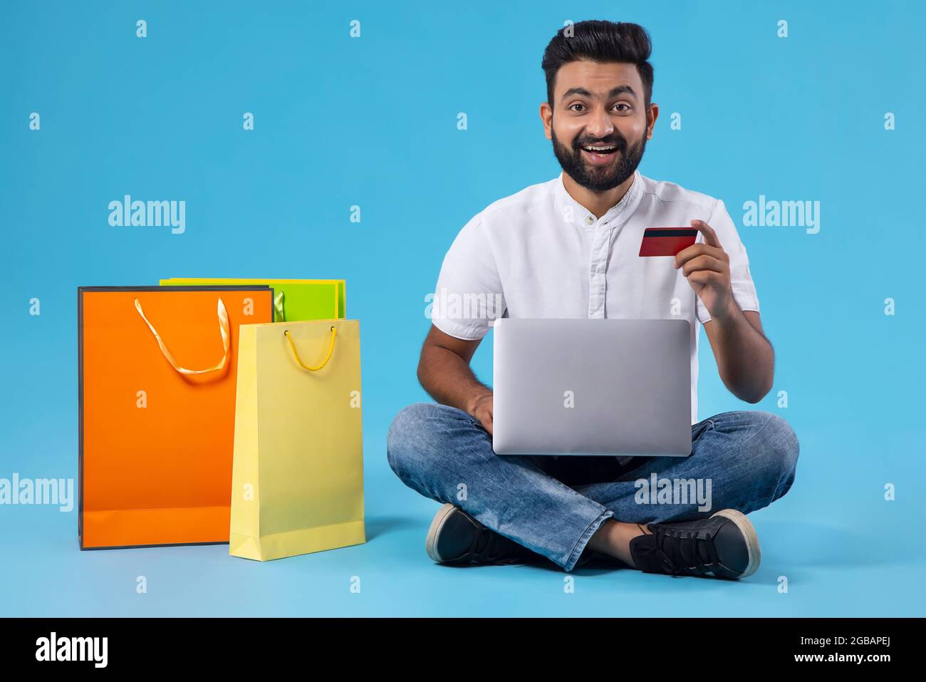 A BEARDED YOUNG MAN HAPPILY USING DEBIT CARD TO DO ONLINE SHOPPING ...