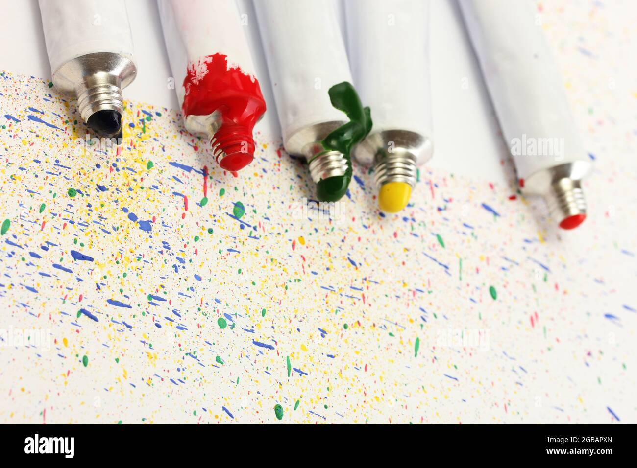 Tubes with colorful watercolors on colorful splash background close-up ...