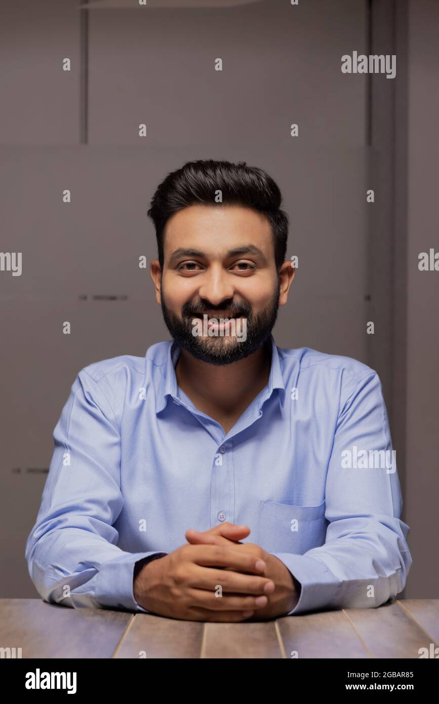 A CHEERFUL YOUNG MAN SITTING IN FRONT OF CAMERA Stock Photo - Alamy