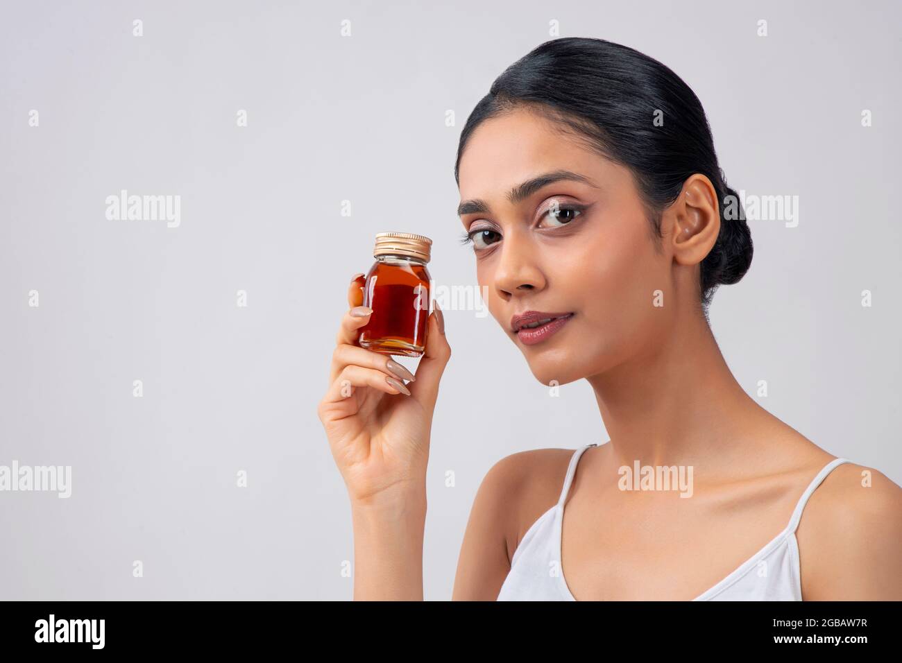 A young woman with clear,spotless skin holding a bottle of honey Stock ...