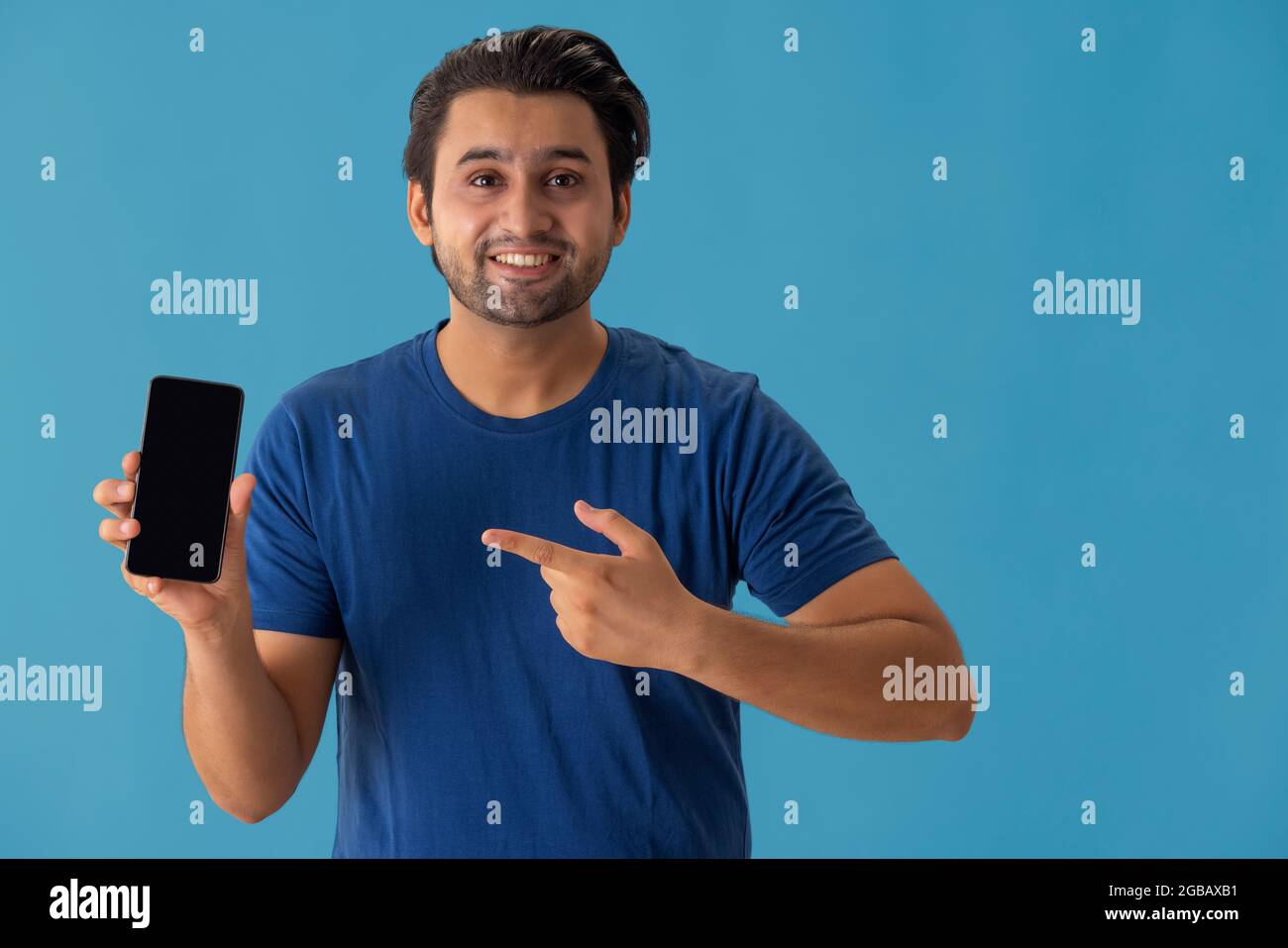 A young man pointing towards mobile phone in his hands Stock Photo - Alamy
