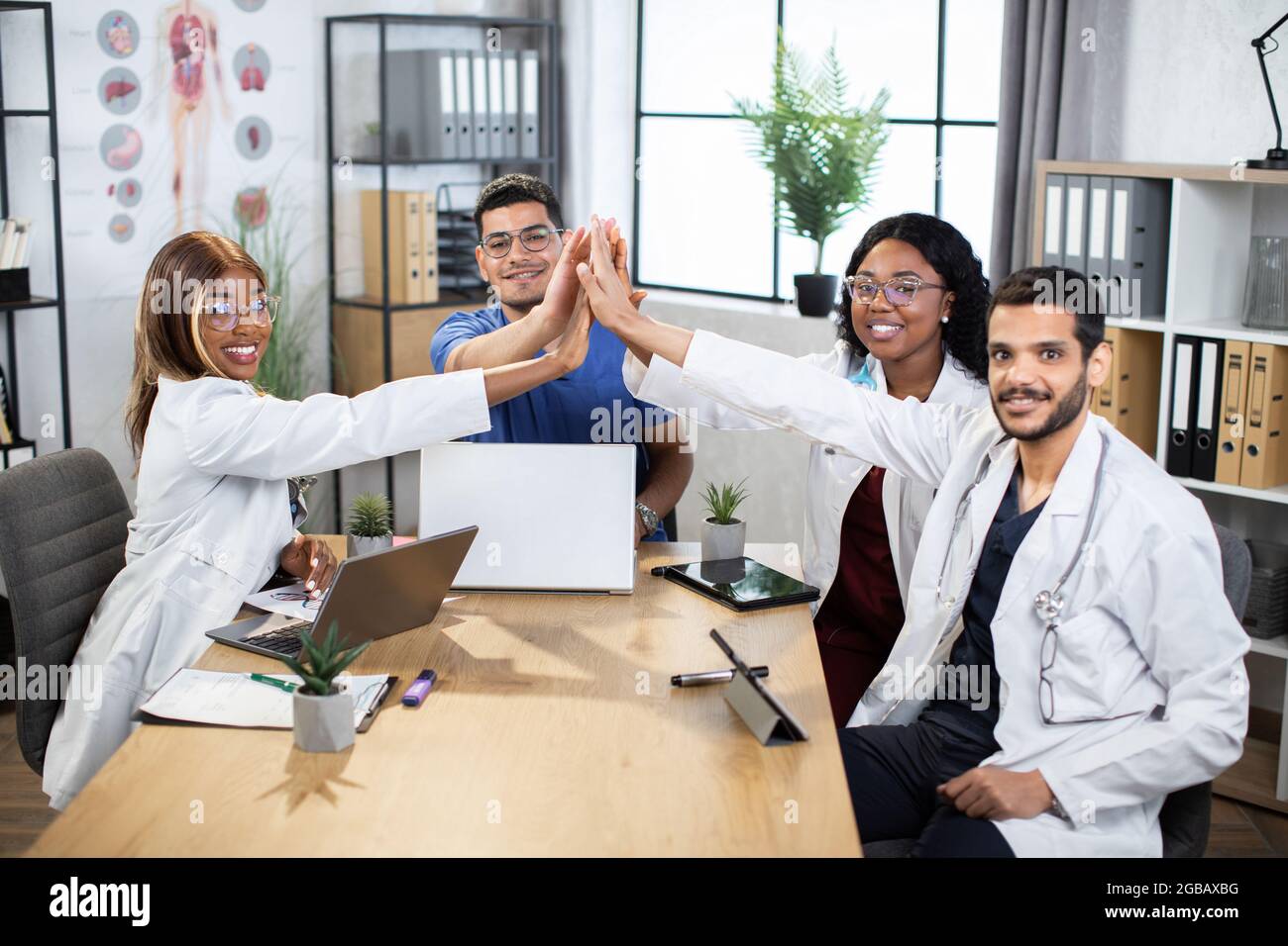 Team of four international doctors giving high five for expressing ...
