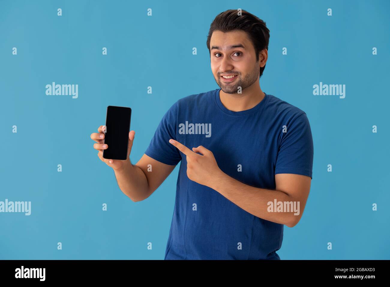 A young man pointing towards mobile phone in his hands Stock Photo - Alamy