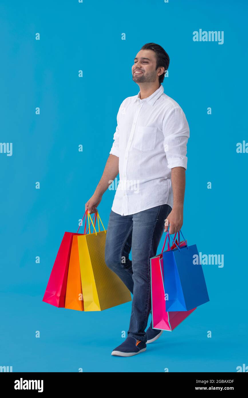 A young man standing with colorful carrybags in his hand Stock Photo ...