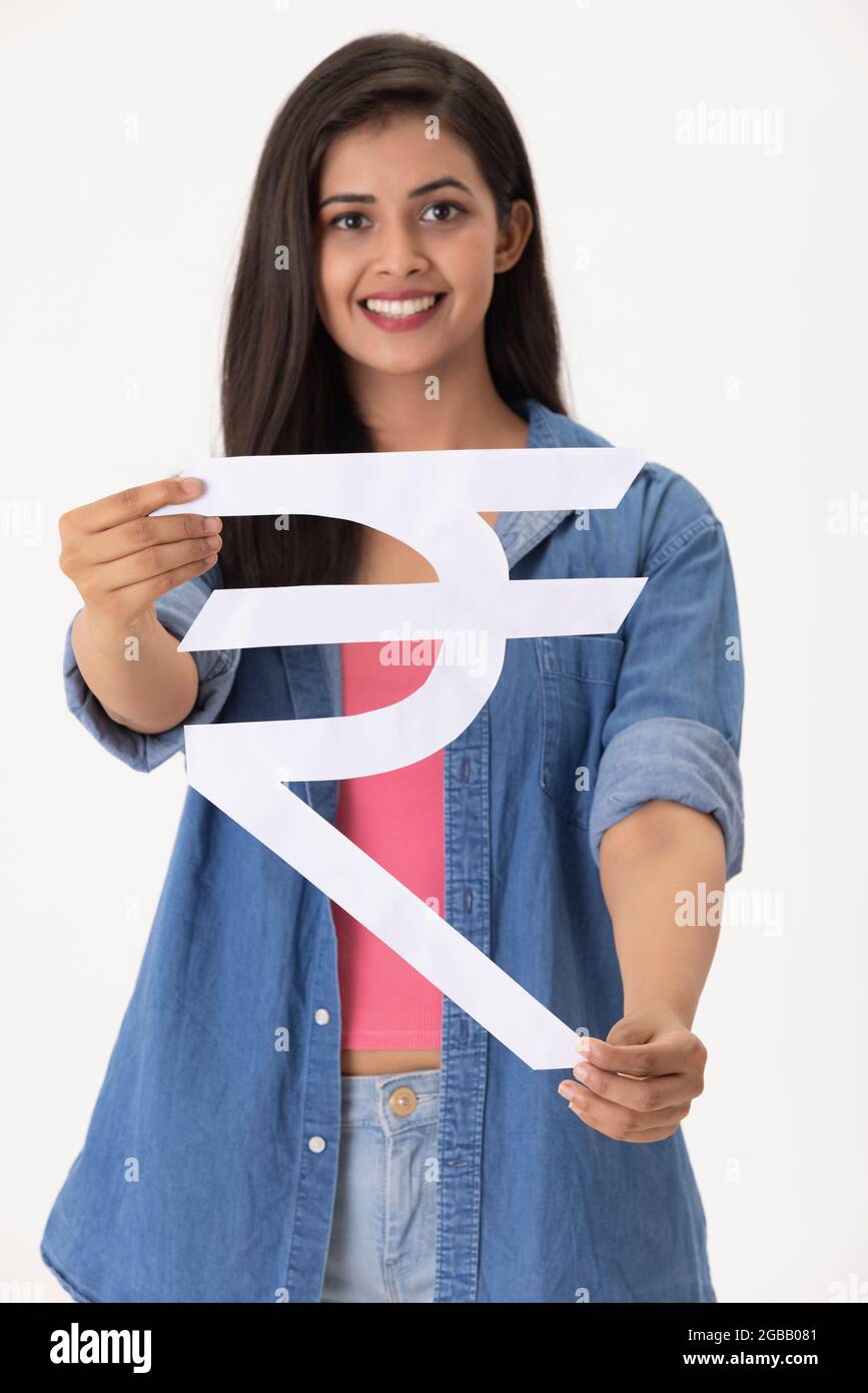 A young woman holding Indian rupee symbol made of cardboard in hand ...