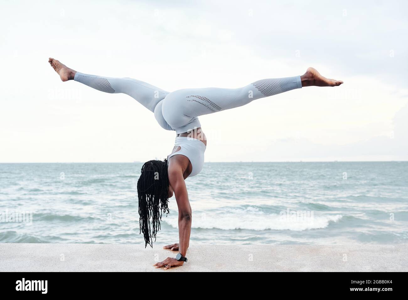 Strong fit young woman doing handstand splits on sandy beach Stock ...