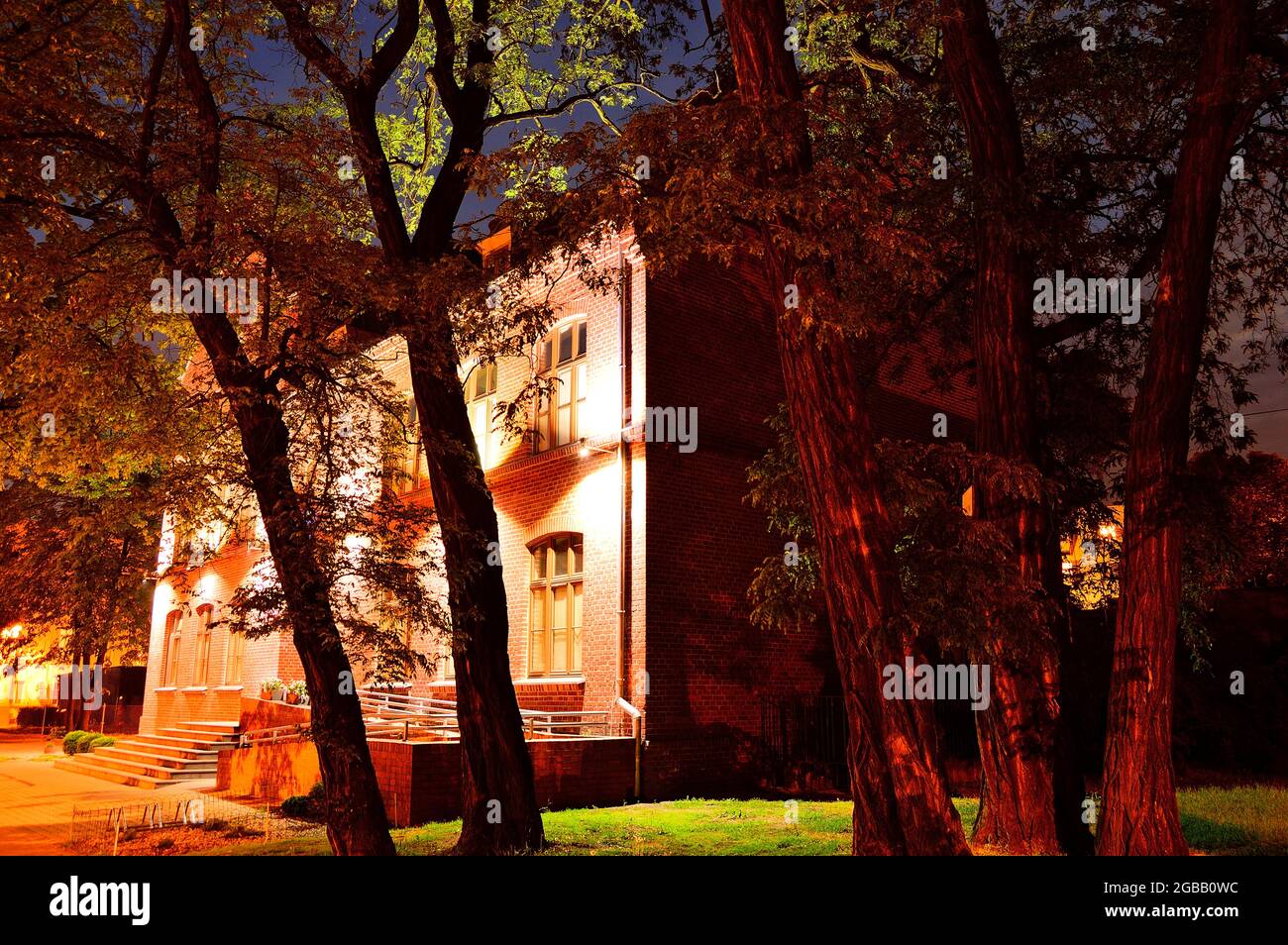 House at night among trees lit by street lamps. City Stock Photo - Alamy