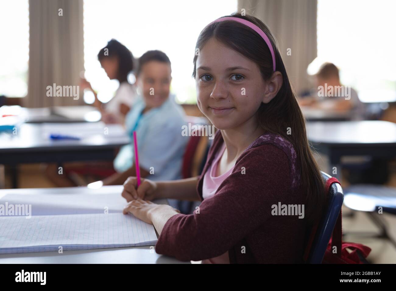 Portrait of caucasian girl sitting on her desk in the class at school ...