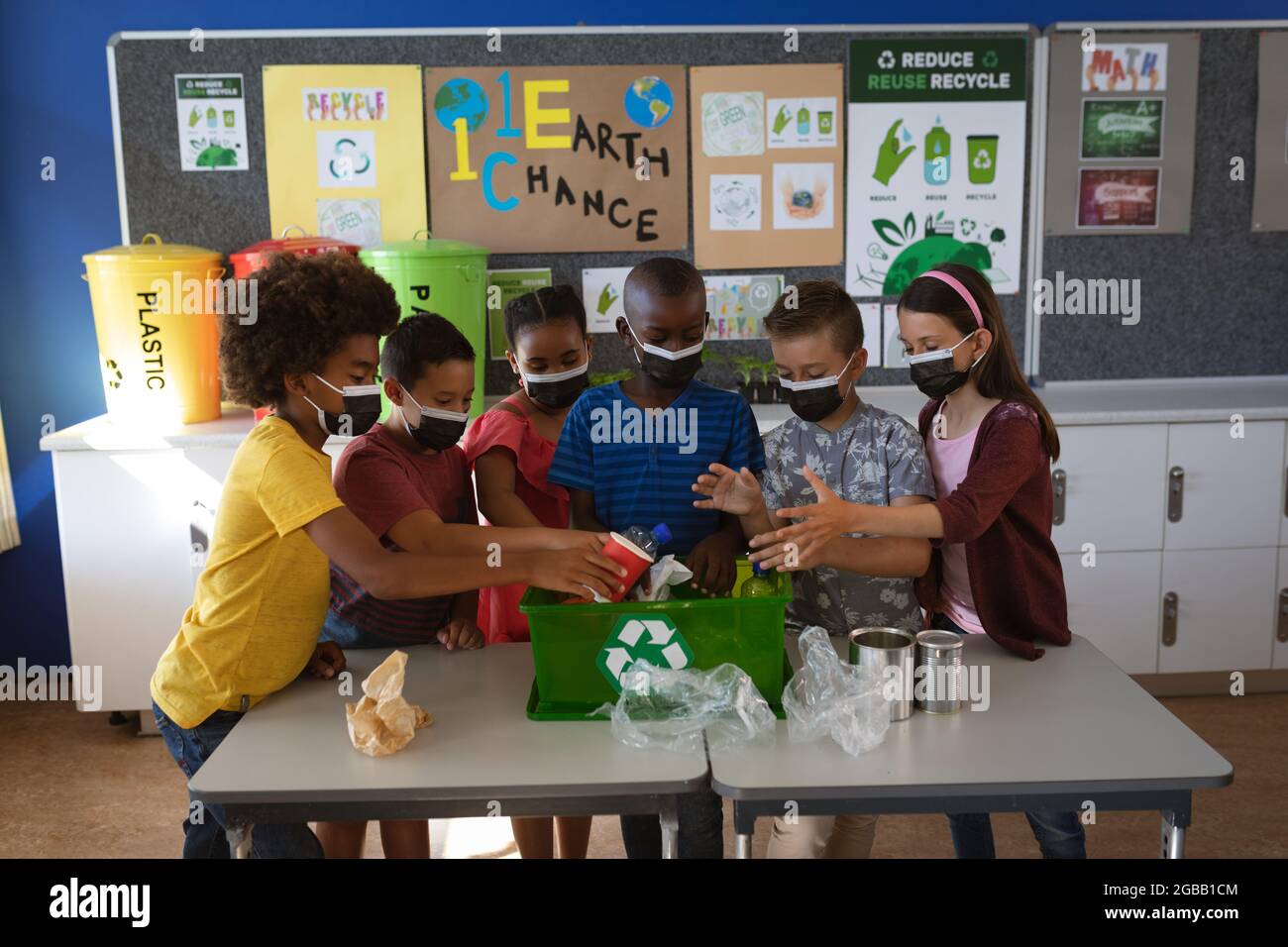 Group of diverse students wearing face masks putting recyclable plastic ...