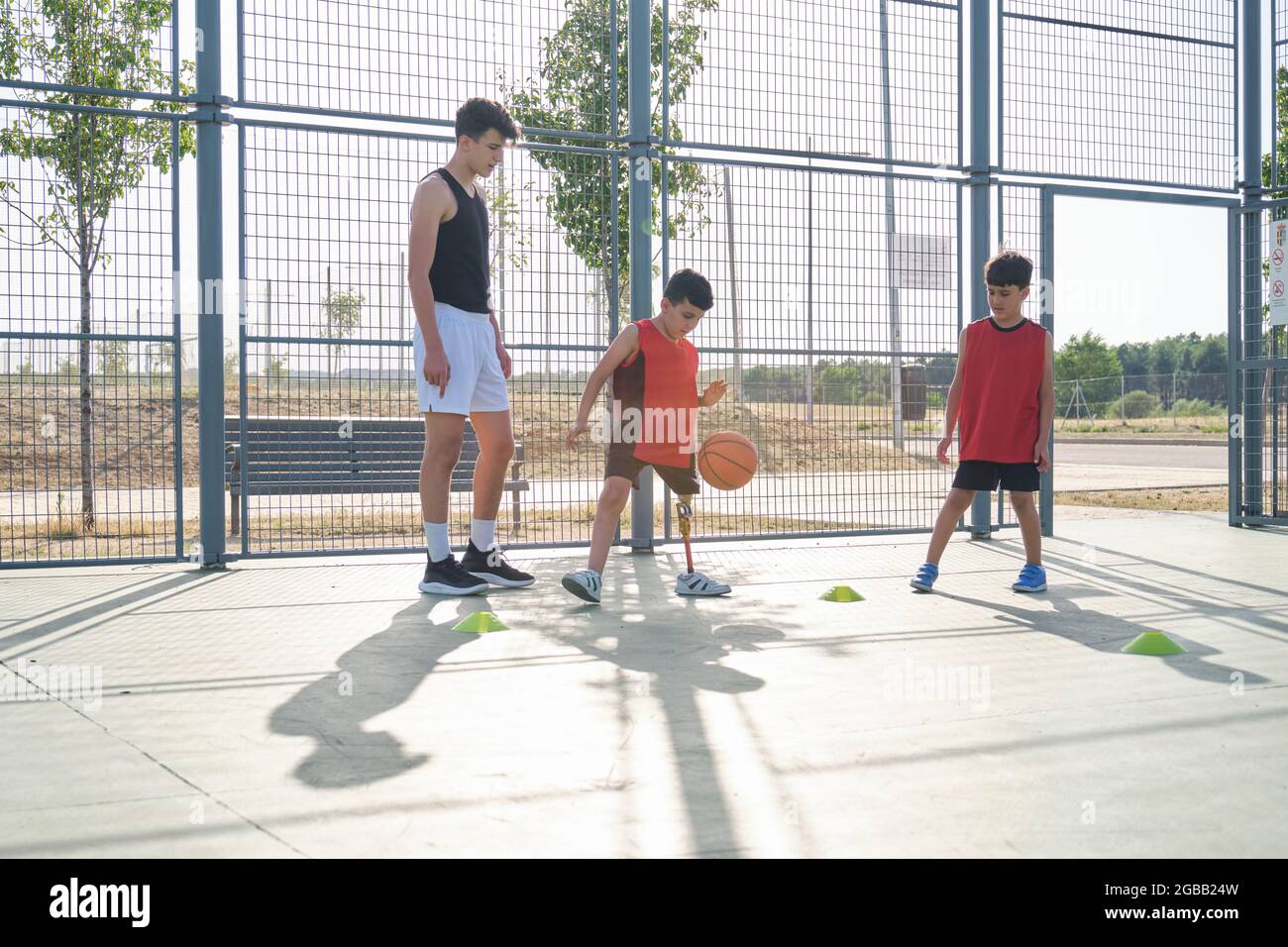 Older brother teaching how to play basketball to his younger siblings ...