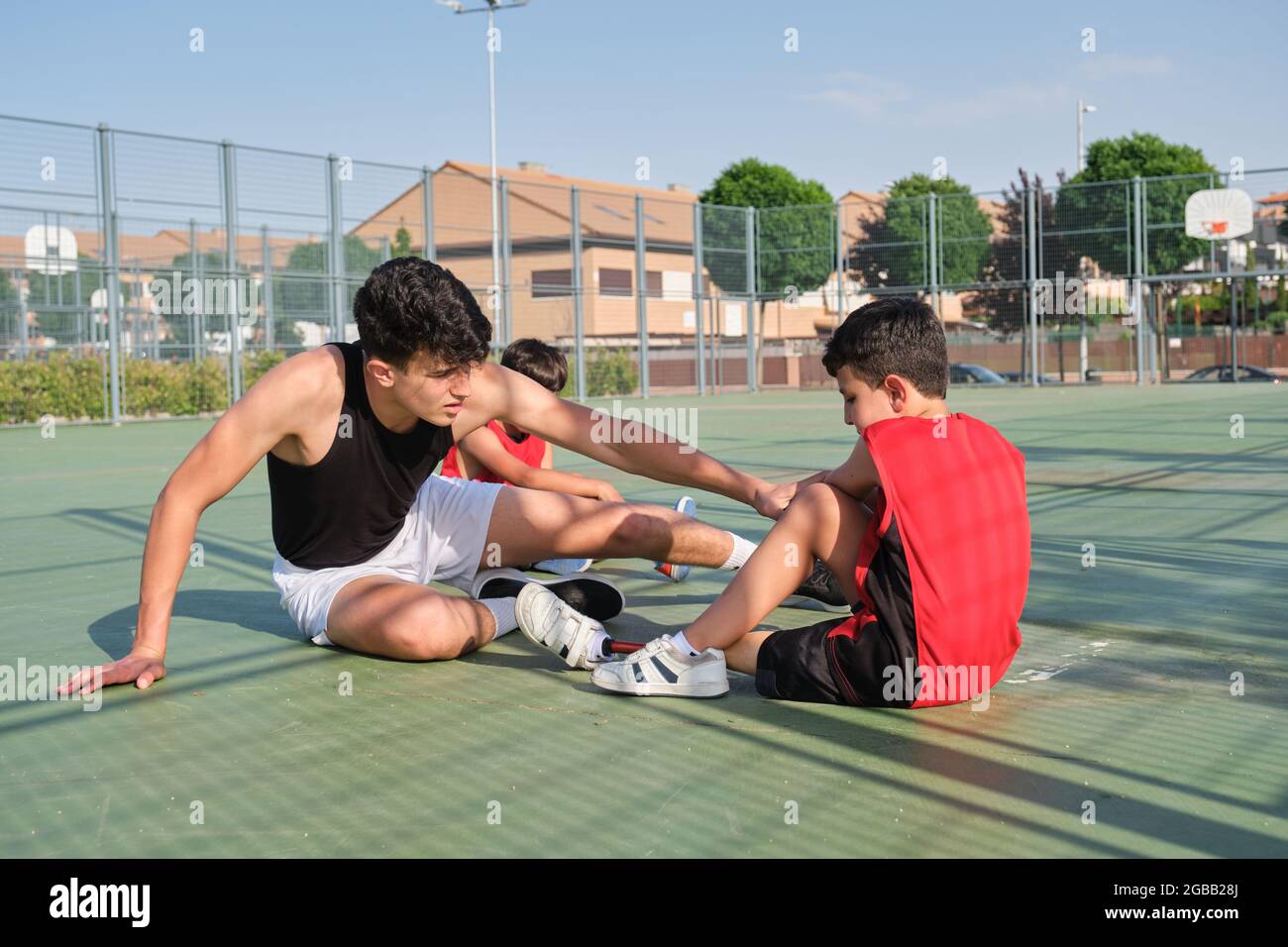 Basket coach teaching how to leg stretching to a leg prosthesis kid ...