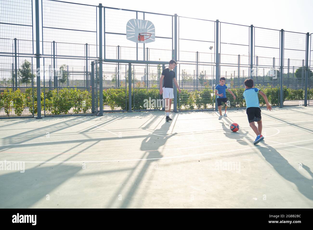 Three brothers play football, one has a prosthesis, other is kicking a ...
