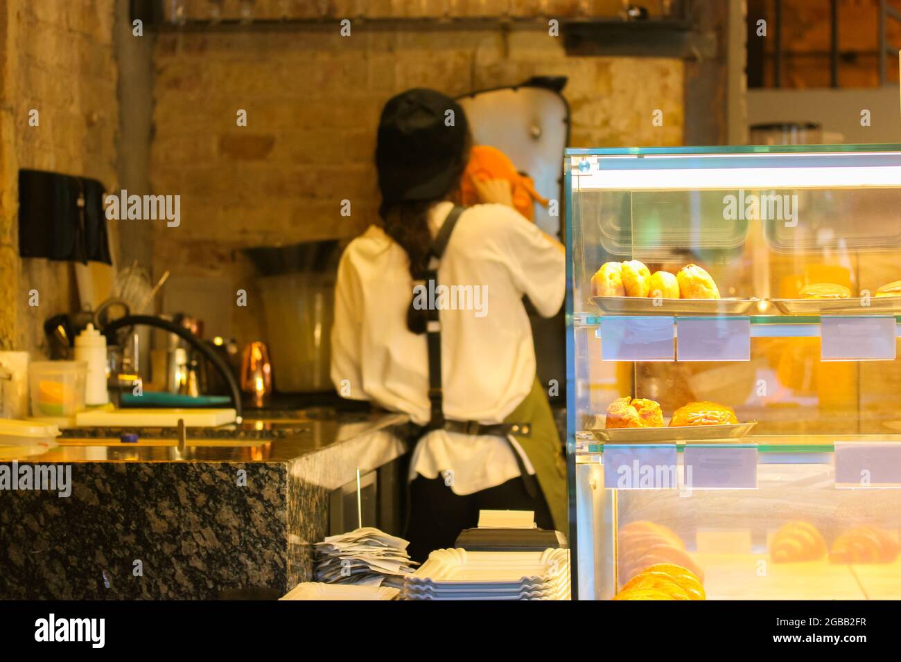 A back view female barista prepares orange juice. An unrecognizable ...