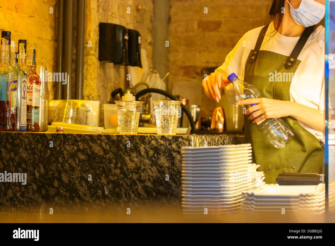A bistro cafe staff, female waitress, wearing a protective medical mask ...