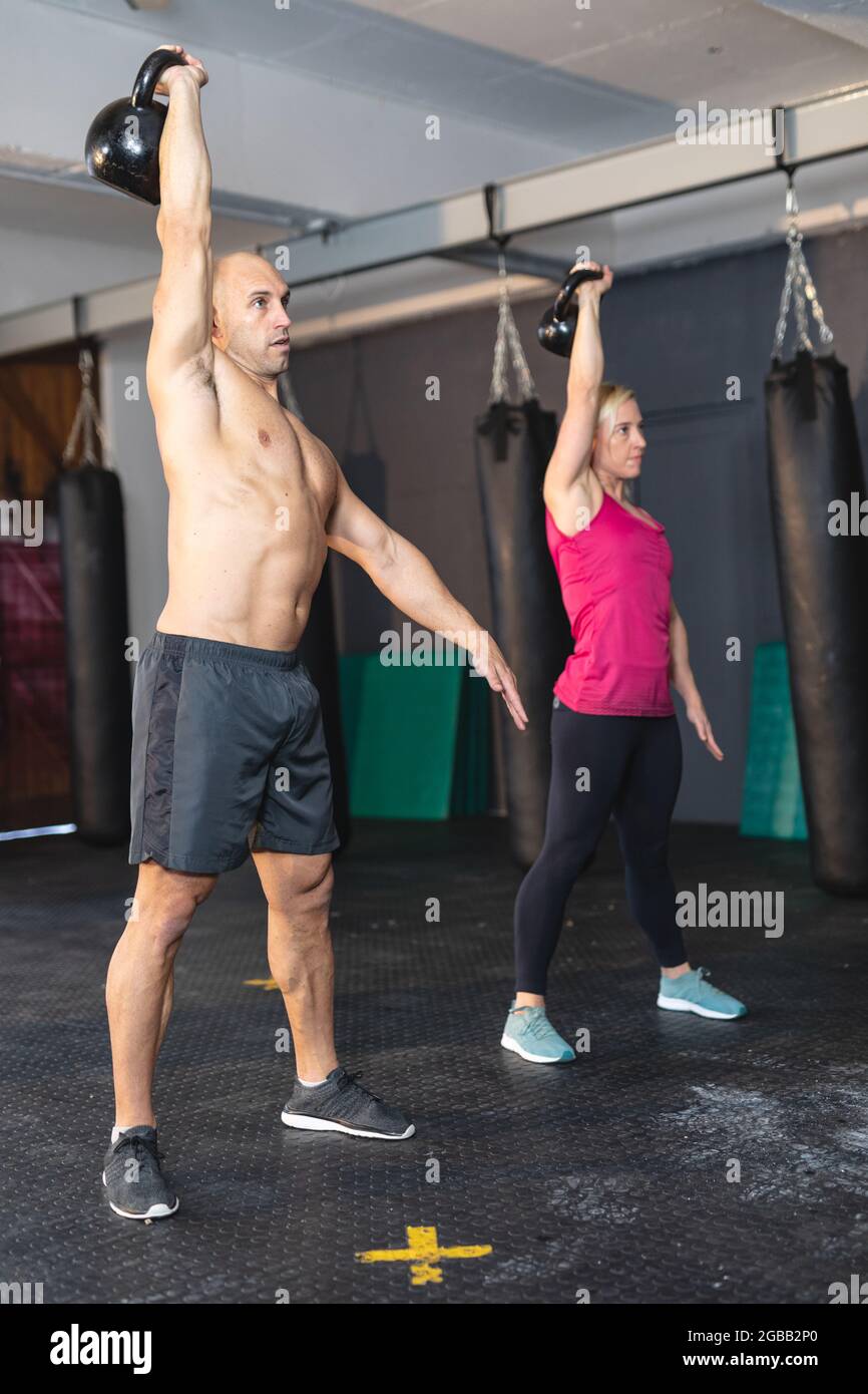 Strong caucasian man and woman exercising at gym, lifting weights Stock ...