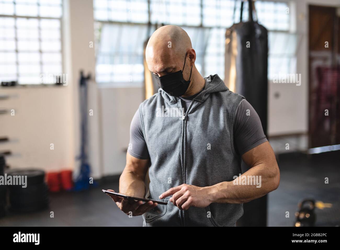 Caucasian male trainer wearing face mask, using tablet Stock Photo - Alamy