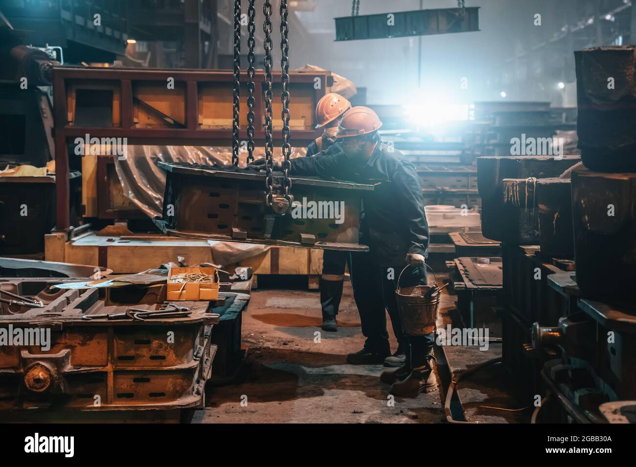 Workers in process of work with large mold iron cast on steel mill ...