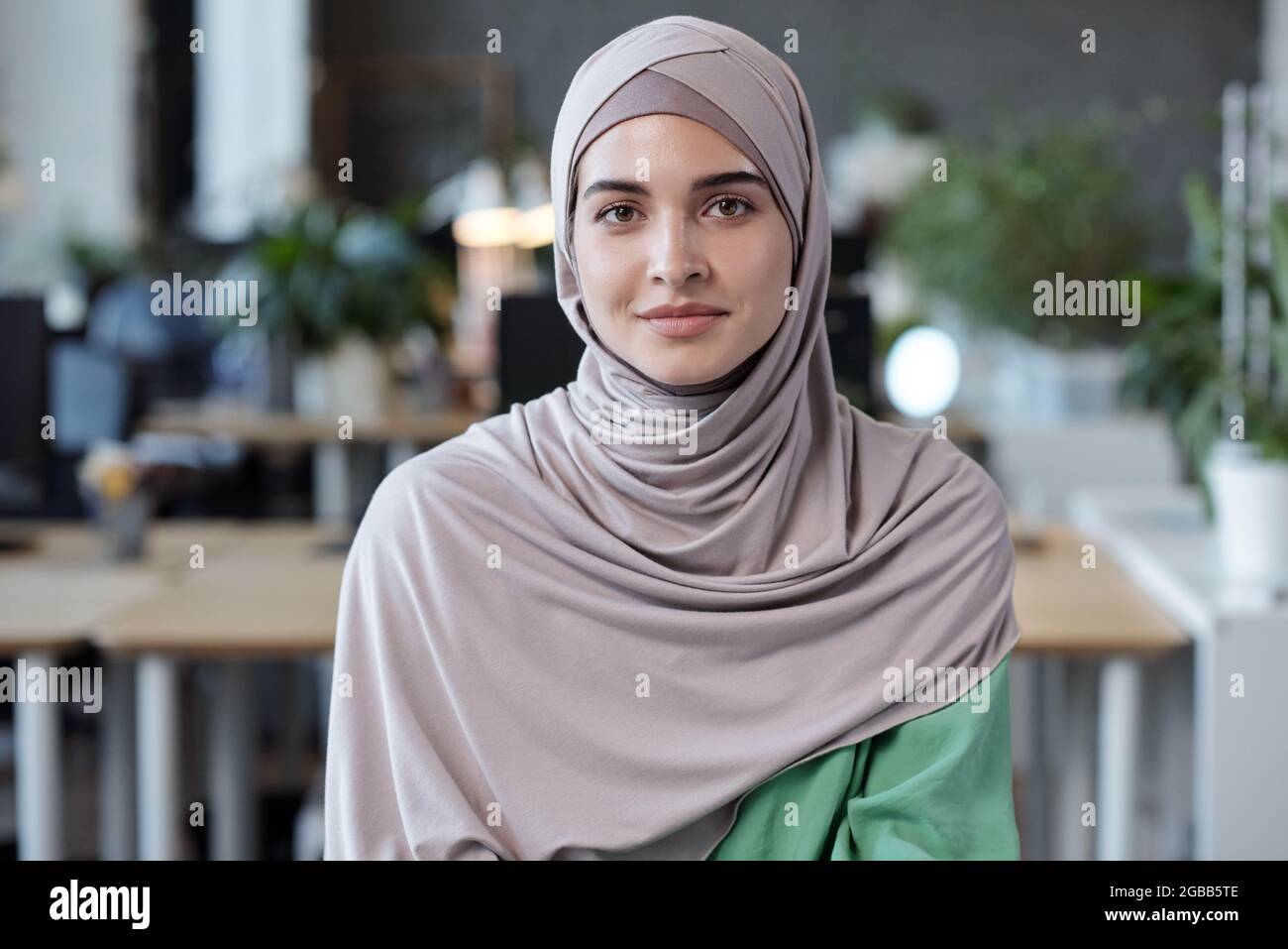 Happy young Muslim female in hijab standing in office environment Stock ...