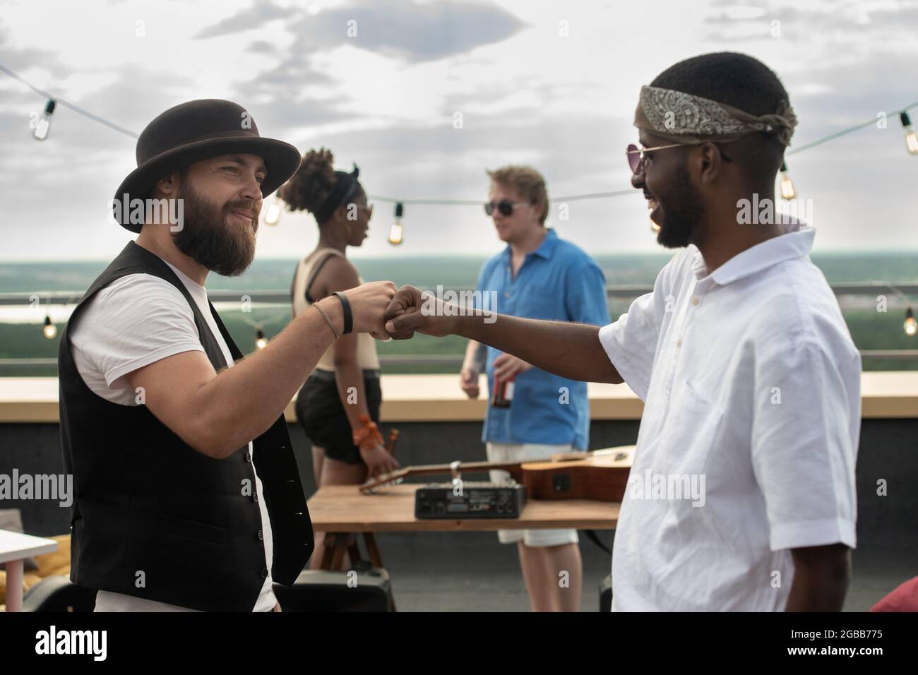 Two young intercultural men greeting each other by punch bump during ...