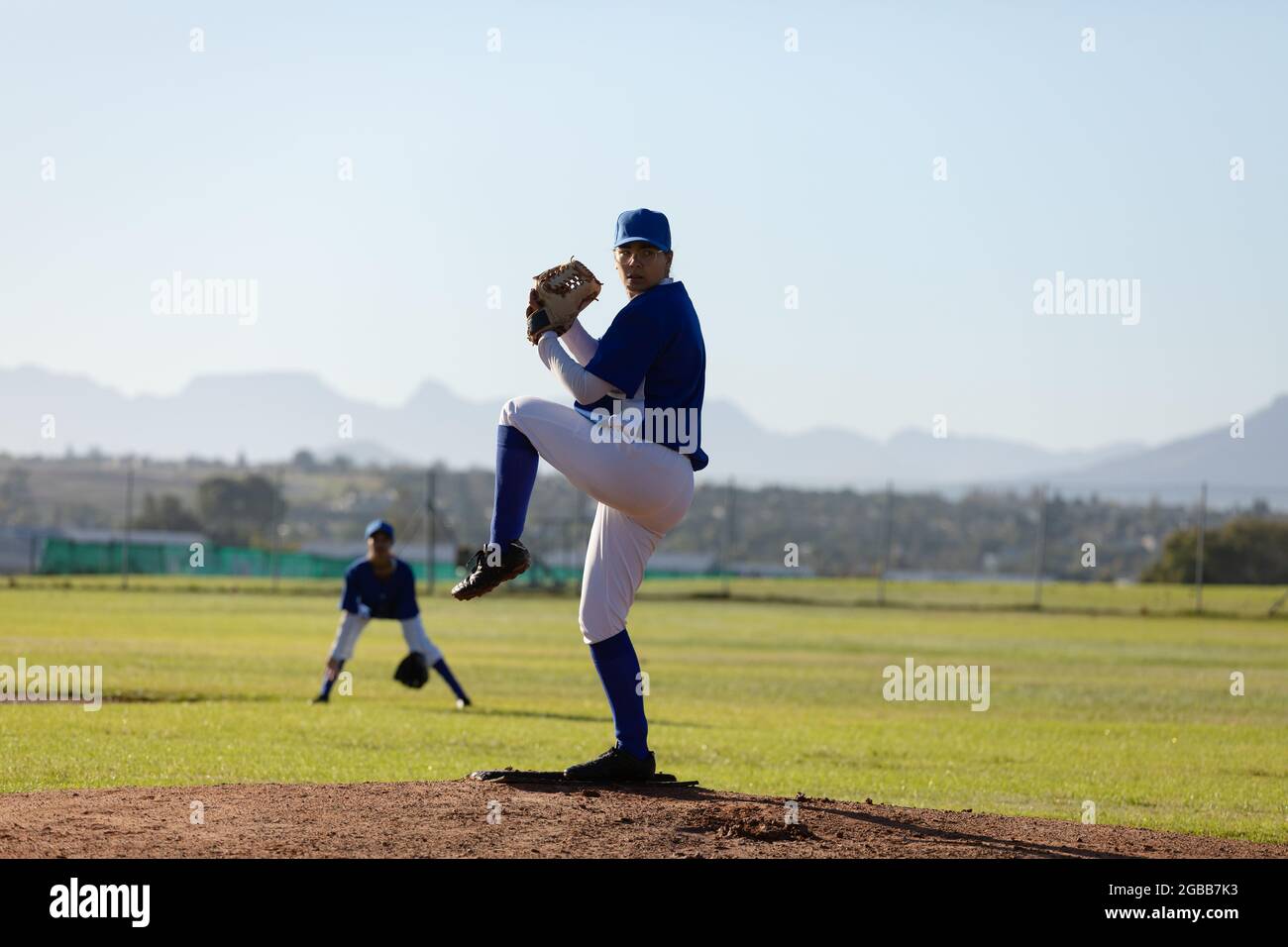 Mixed race female baseball pitcher on sunny baseball field preparing to ...