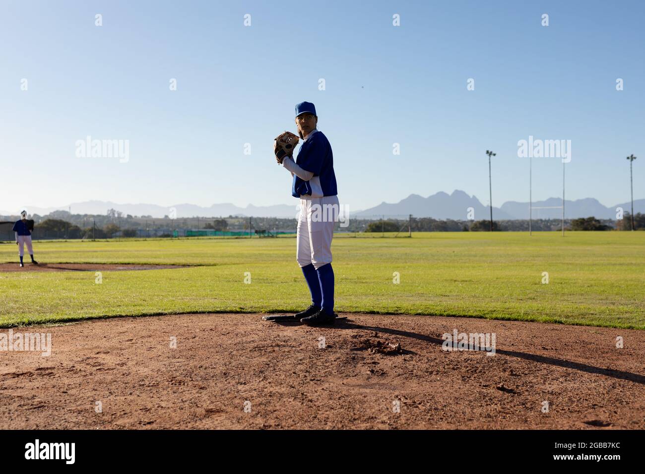 Mixed race female baseball pitcher on sunny baseball field preparing to ...