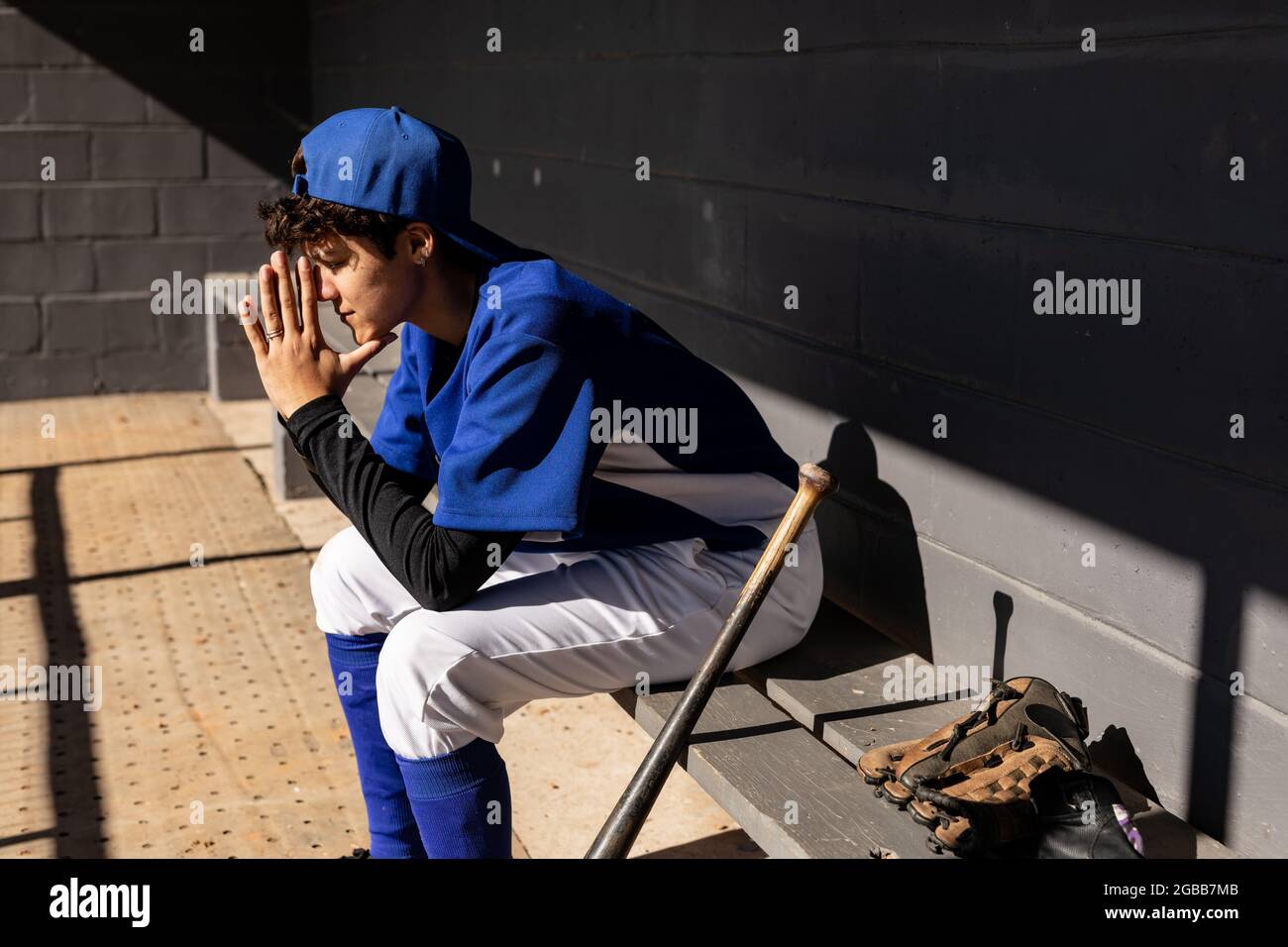 Mixed race female baseball player sitting on bench with bat preparing ...