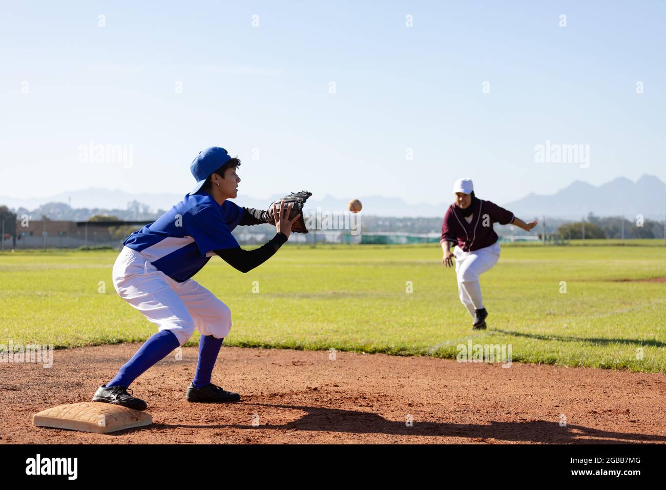 Mixed race female baseball player on sunny baseball field reaching to ...